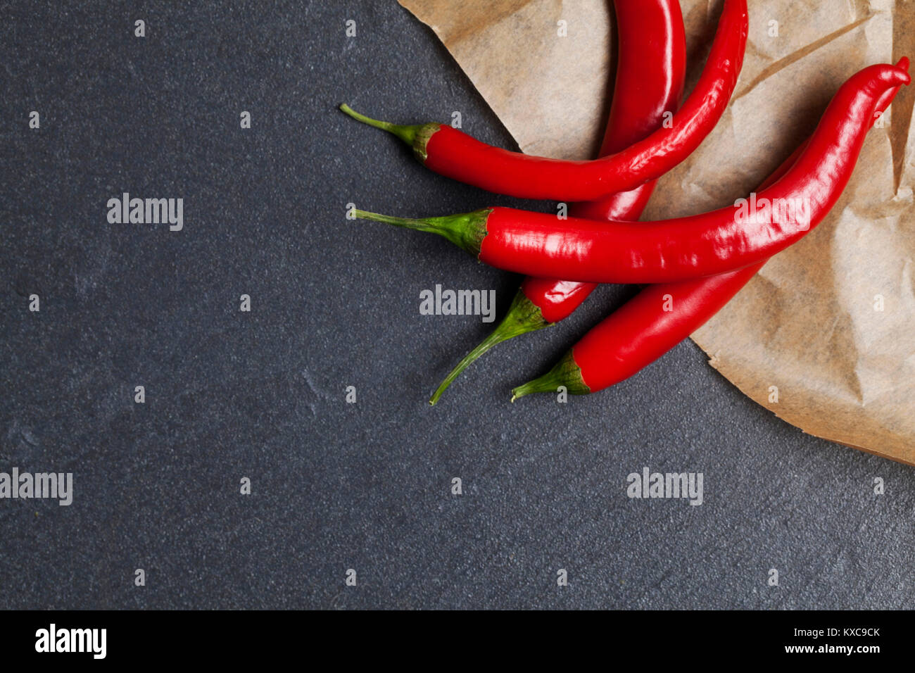 Red fresh chili peppers on parchment and slate background Stock Photo ...