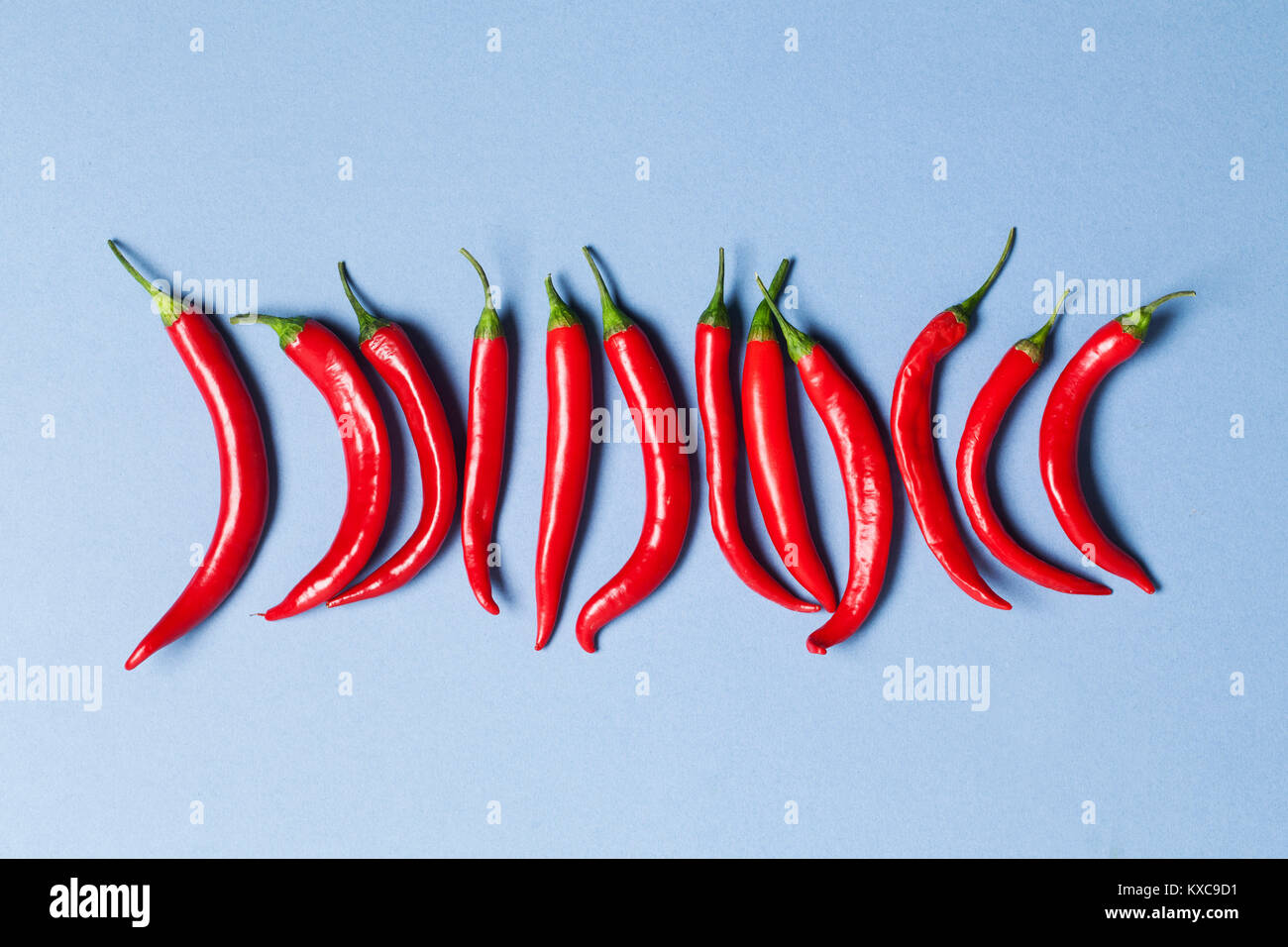 Red chili peppers arranged on a light blue background Stock Photo - Alamy