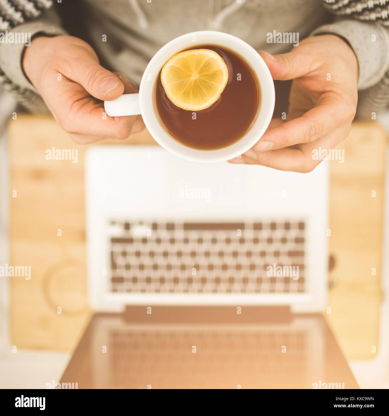 Top view hands with cup of tea with lemon and laptop Stock Photo - Alamy
