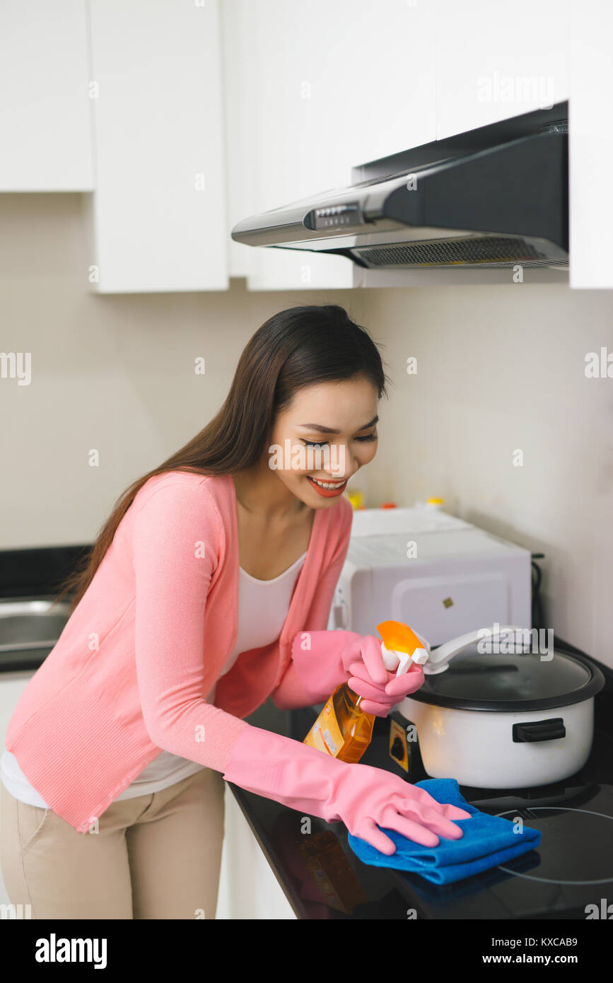 Portrait of attractive young woman cleaning a surface of white kitchen ...