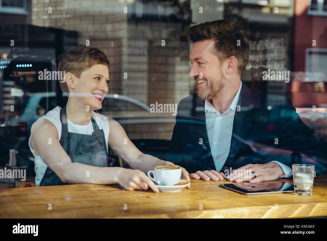 Waitress serving coffee to smiling customer in cafe Stock Photo - Alamy