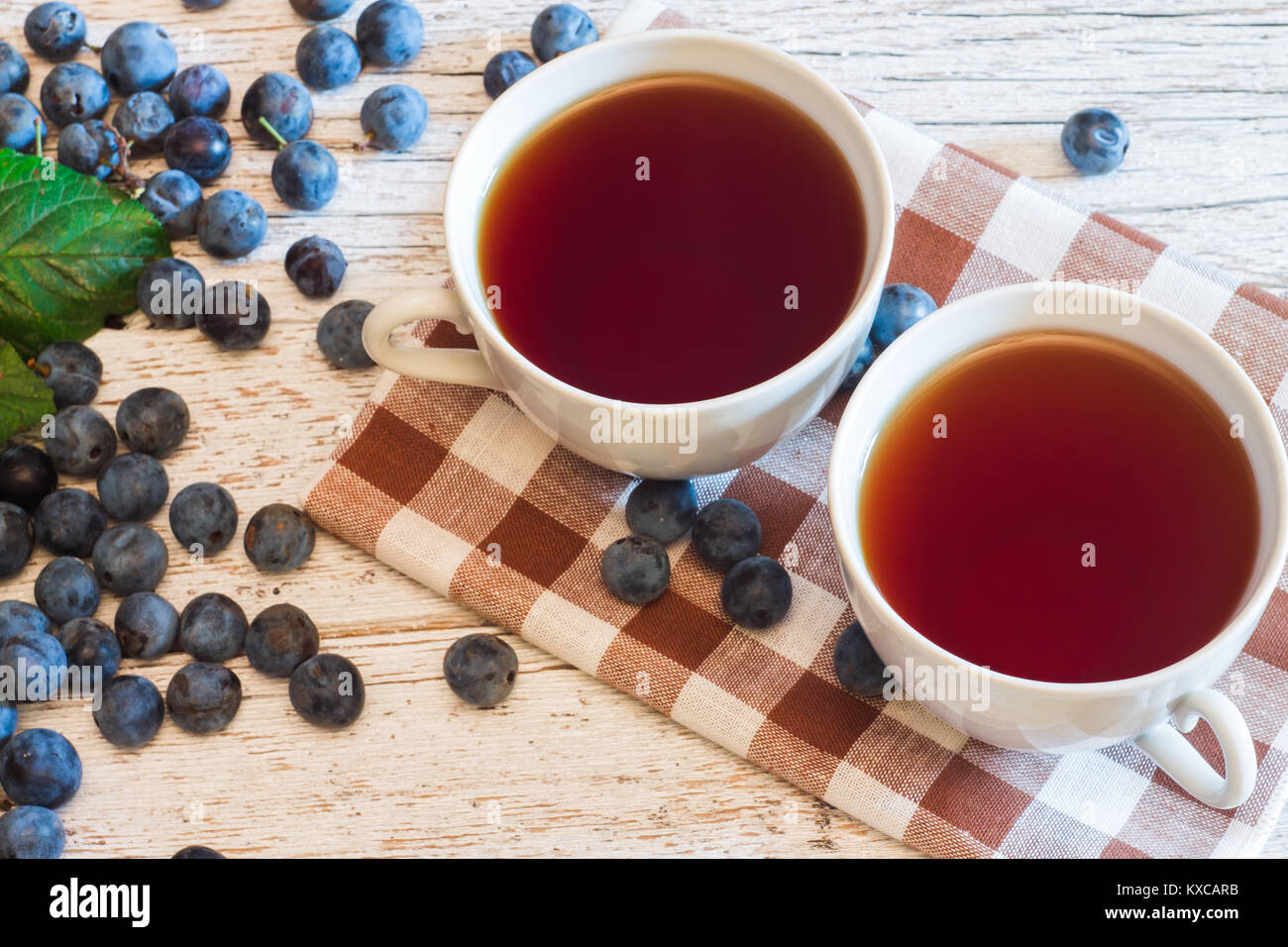 two cups of tea closeup on a napkin on white wooden background with ...