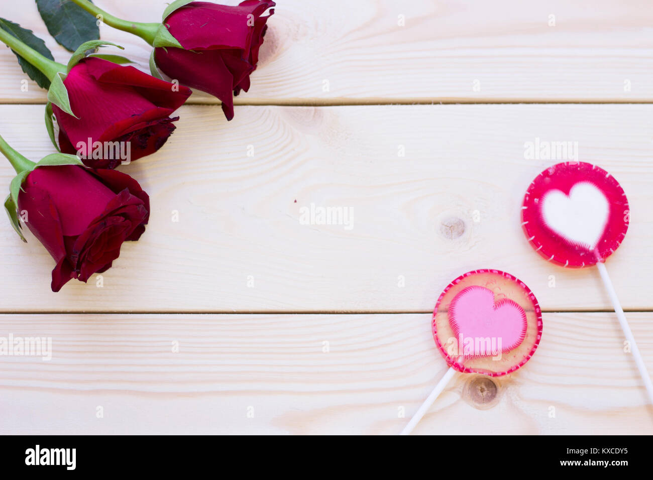 Wooden background with red roses and lolipops Stock Photo - Alamy
