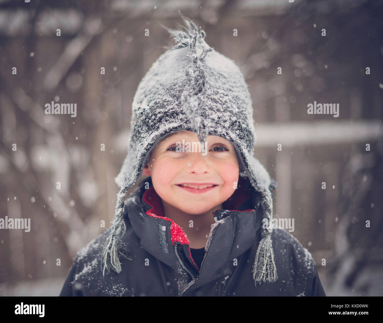 Portrait of cheerful boy wearing hat during snowfall Stock Photo - Alamy