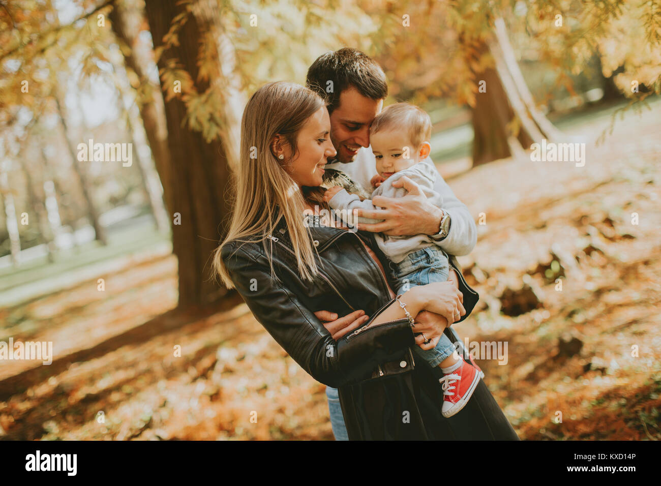 Happy young parents have fun with baby boy in autumn park Stock Photo ...
