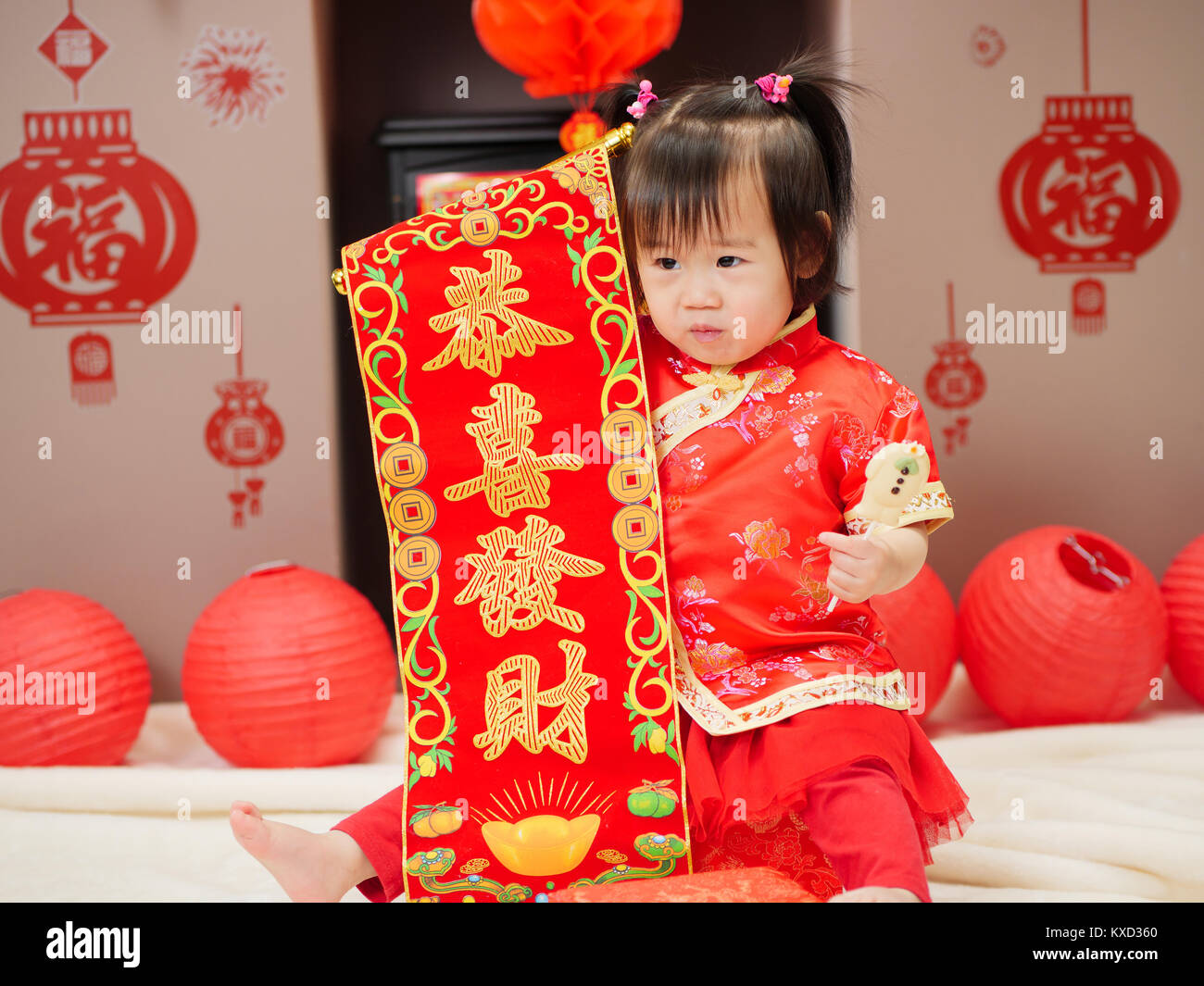 Chinese baby girl traditional dressing up with a Gong Xi Fa Cha scrolls ...