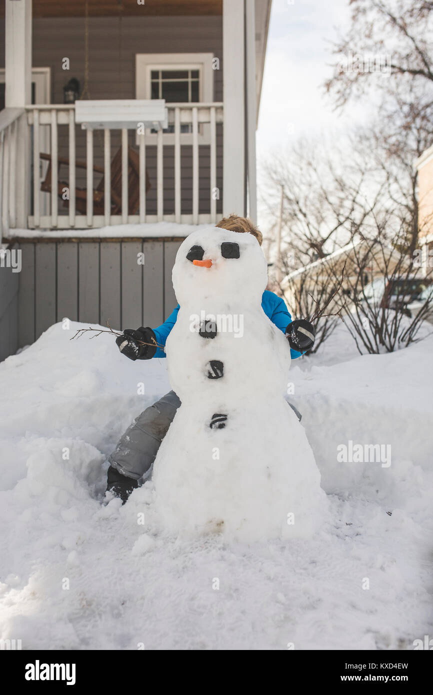 Boy making snowman in yard Stock Photo - Alamy