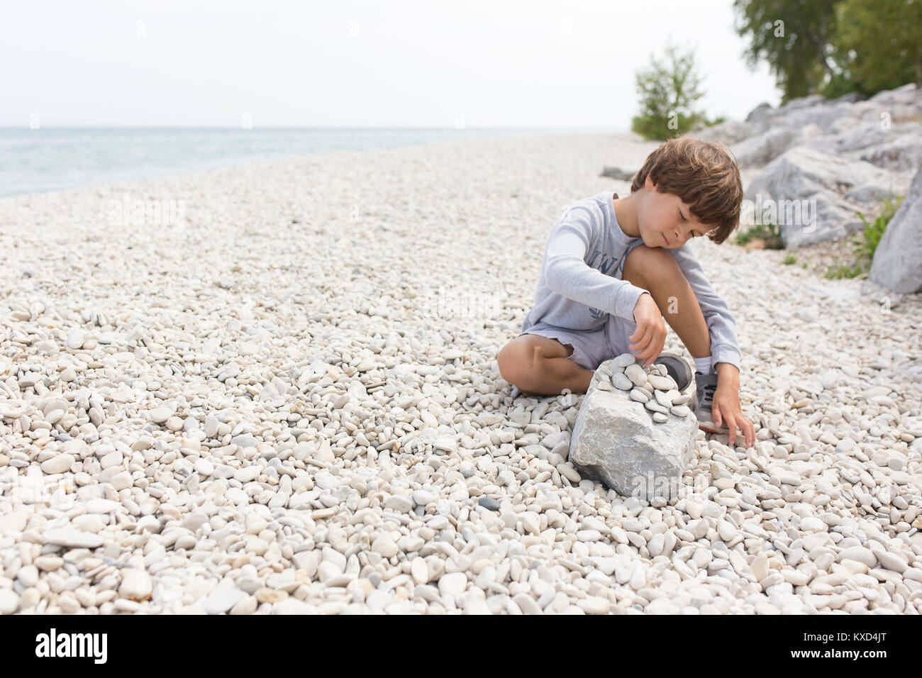Carefree boy playing with pebbles at lakeshore Stock Photo - Alamy