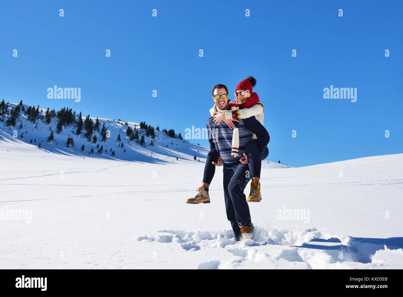 Young couple having fun on snow. Happy man at the mountain giving ...