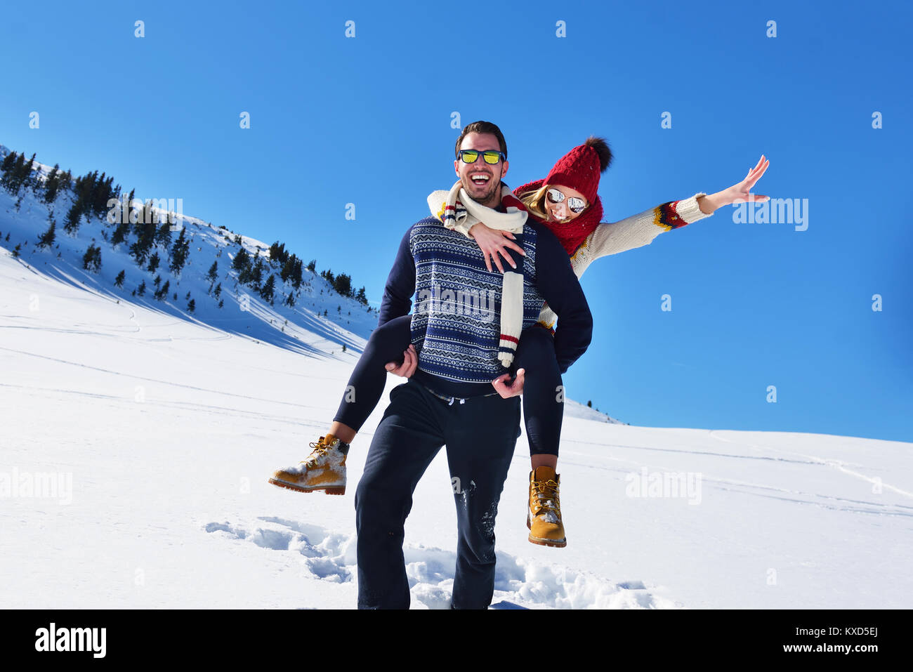 Young couple having fun on snow. Happy man at the mountain giving ...