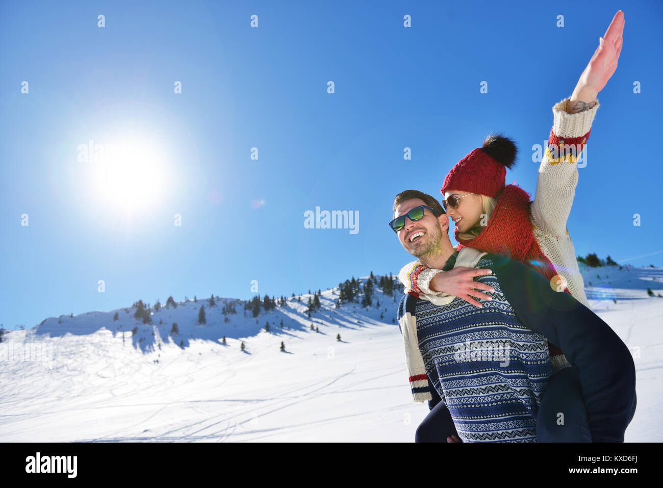 Young couple having fun on snow. Happy man at the mountain giving ...