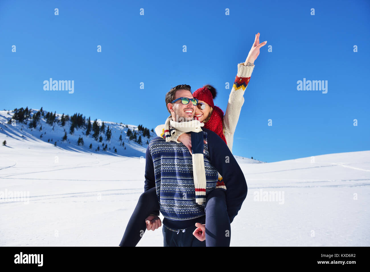 Young couple having fun on snow. Happy man at the mountain giving ...