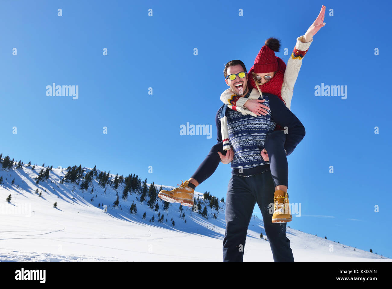 Young couple having fun on snow. Happy man at the mountain giving ...