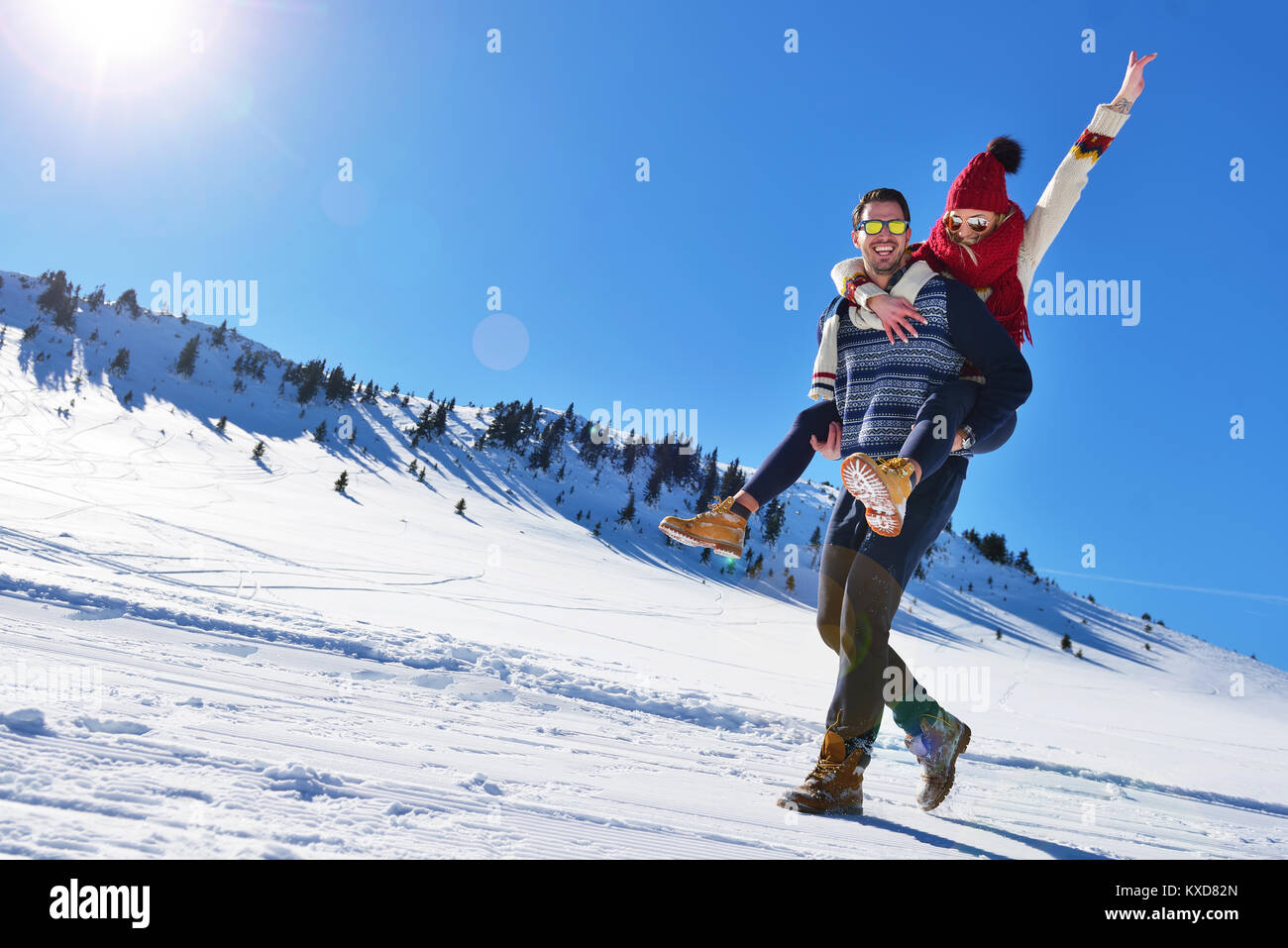 Young couple having fun on snow. Happy man at the mountain giving ...