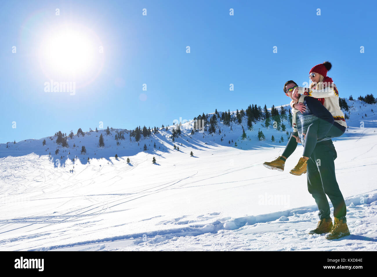 Young couple having fun on snow. Happy man at the mountain giving ...