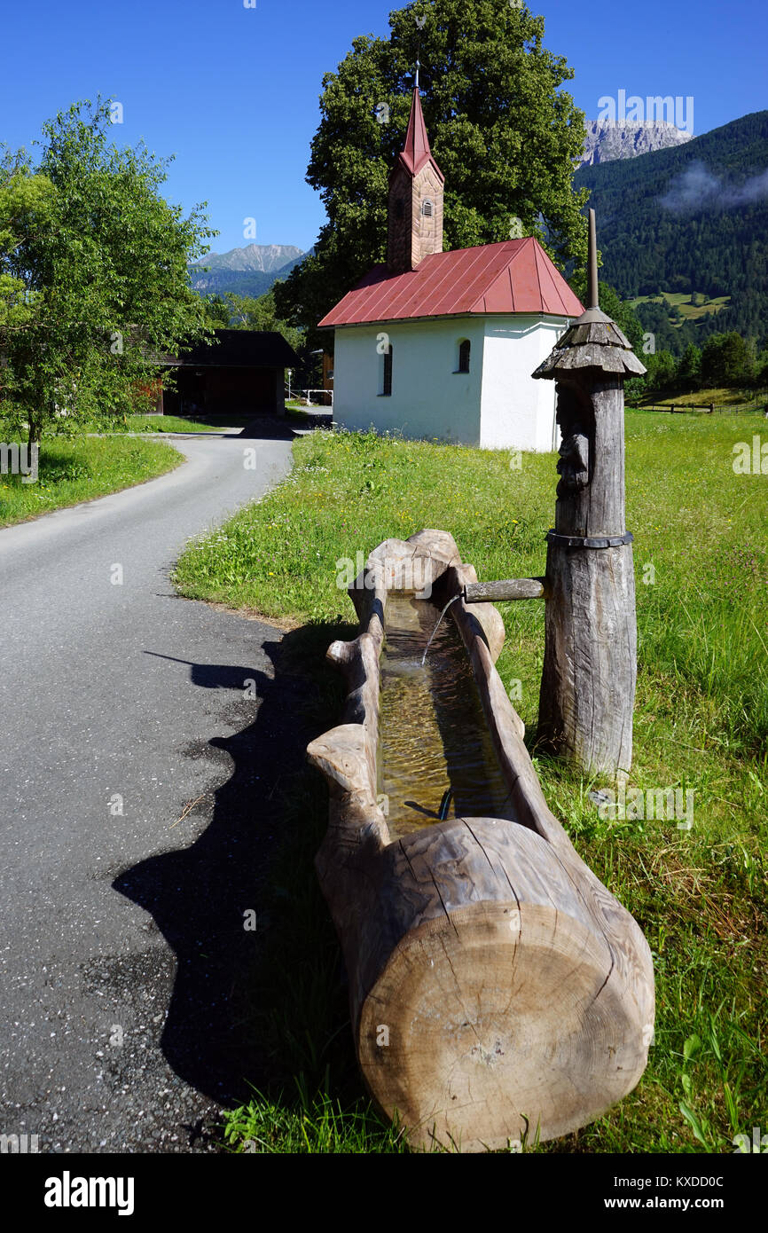 Spring and wooden trough near church in Austria Stock Photo - Alamy