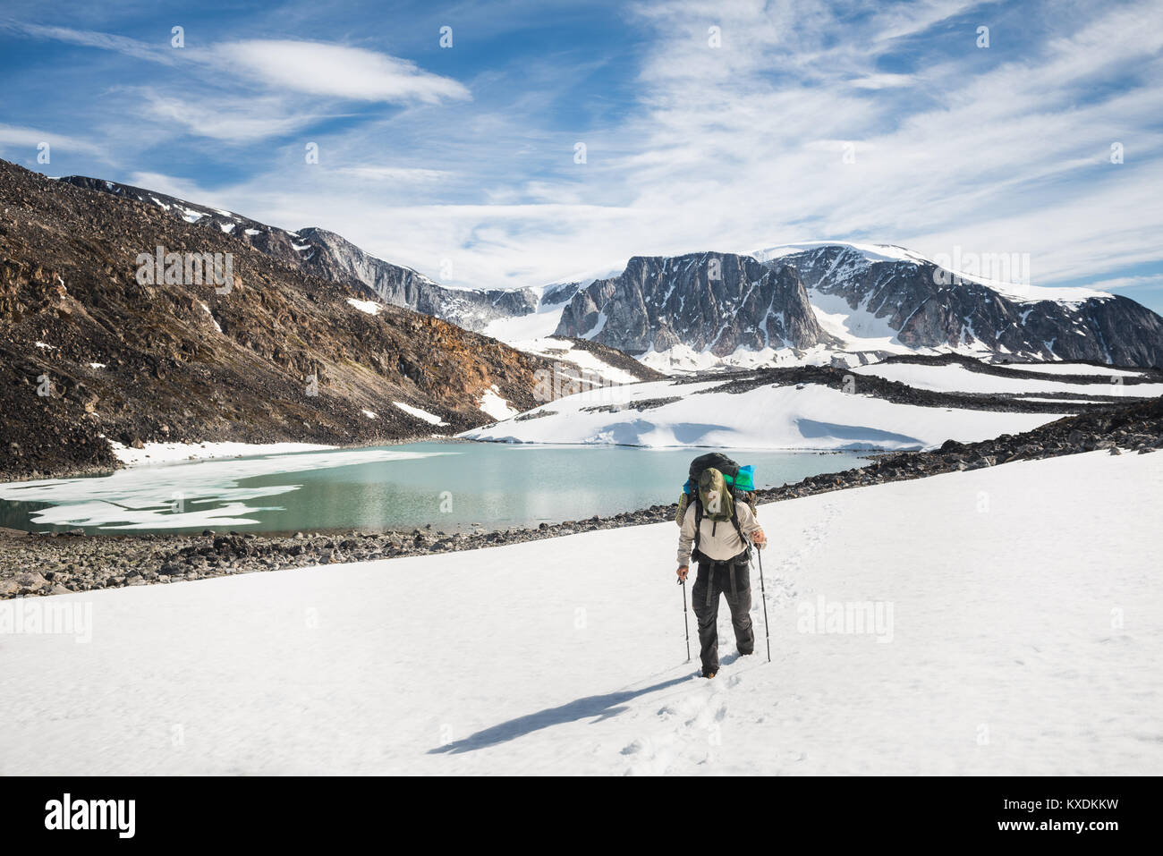 Man trekking in the snow, mountain landscape with lake, West Greenland ...