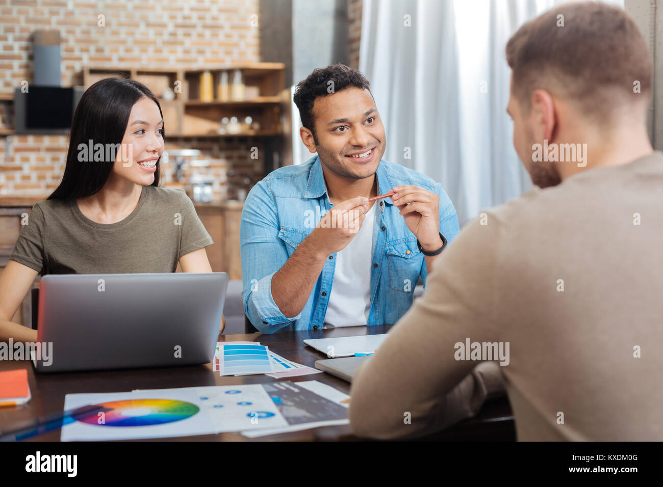Positive young man smiling while his beautiful colleague looking at him ...