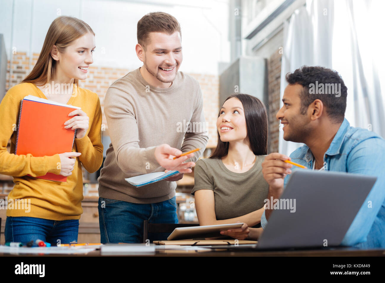 Positive students smiling cheerfully while studying together Stock ...