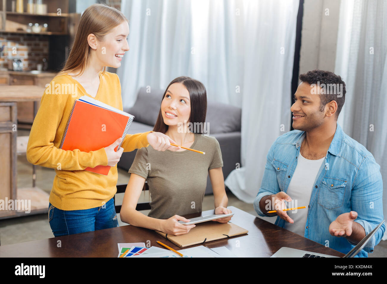 Positive students discussing their homework while sitting together ...