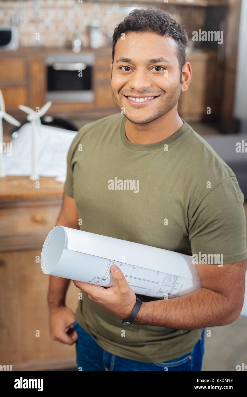 Emotional cheerful engineer holding a drawing while standing and ...