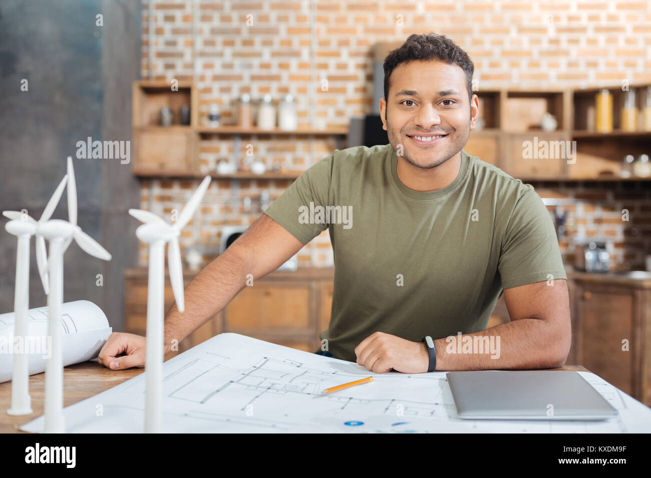 Handsome smart engineer feeling happy while sitting at the table with ...