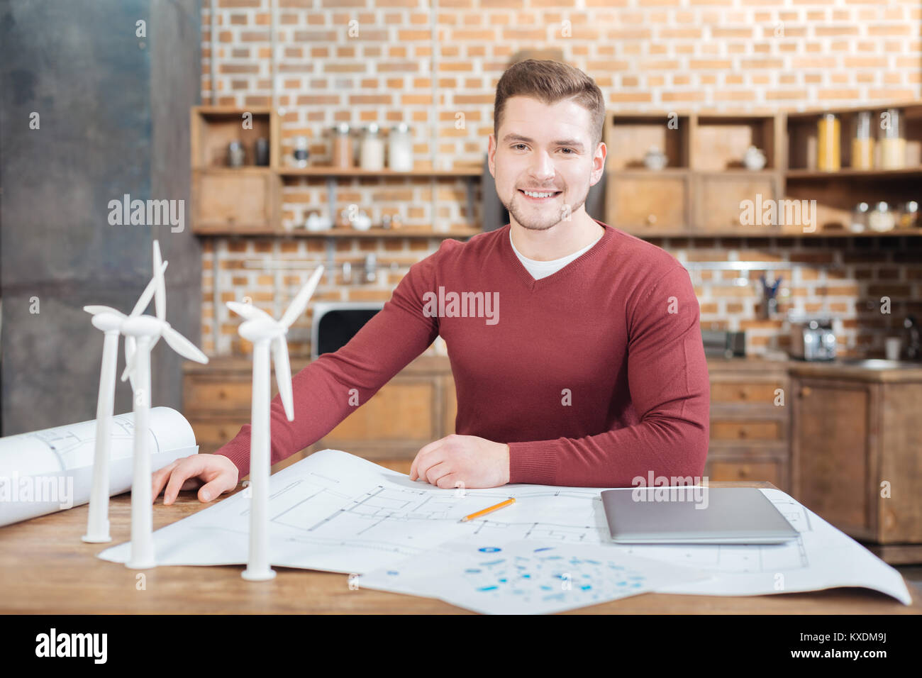 Smiling positive engineer sitting at the table and waiting for his ...