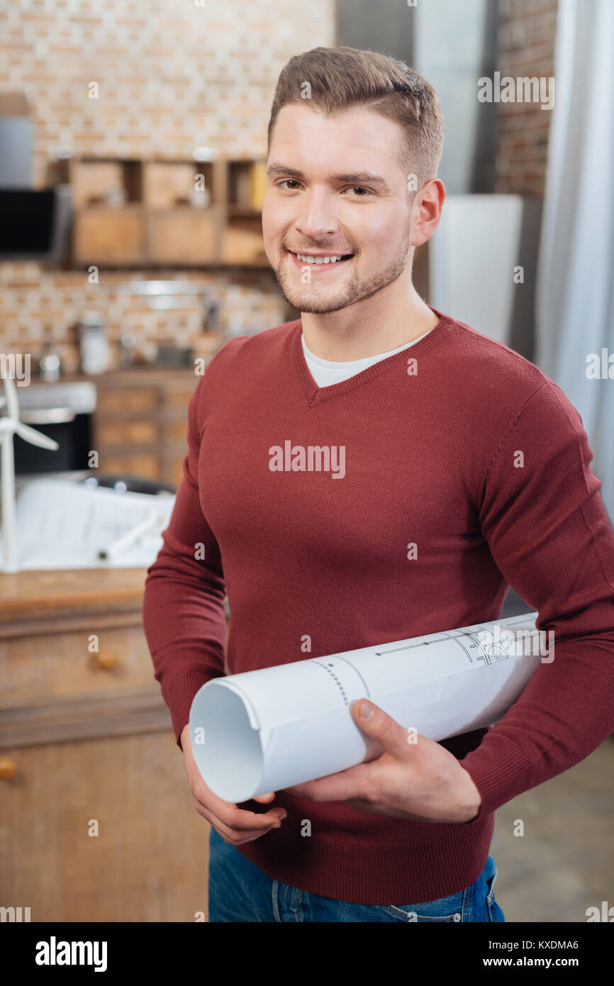 Emotional skilled engineer holding his drawing while standing alone ...