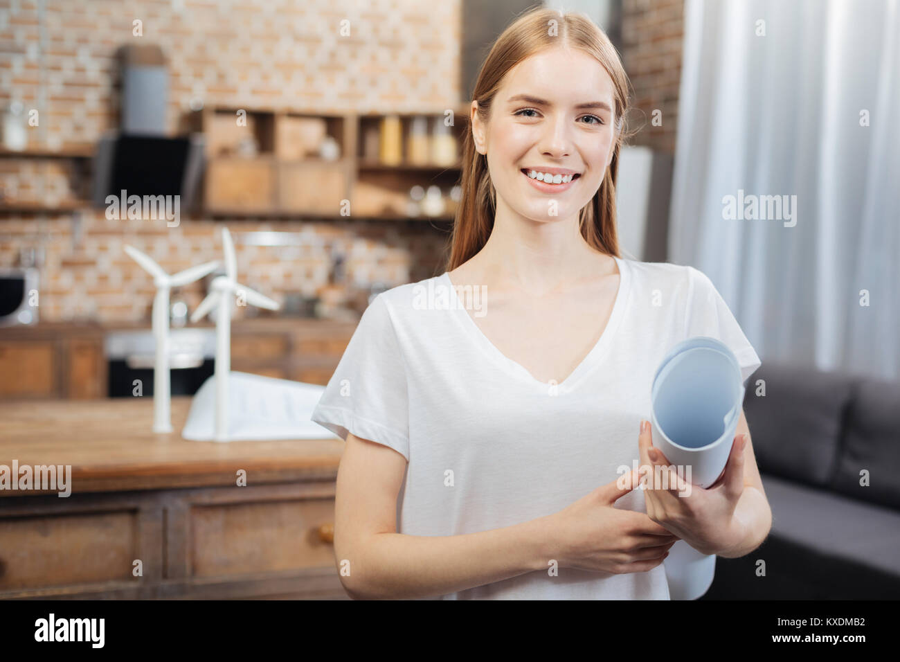 Cute positive worker standing with important drawing and smiling ...