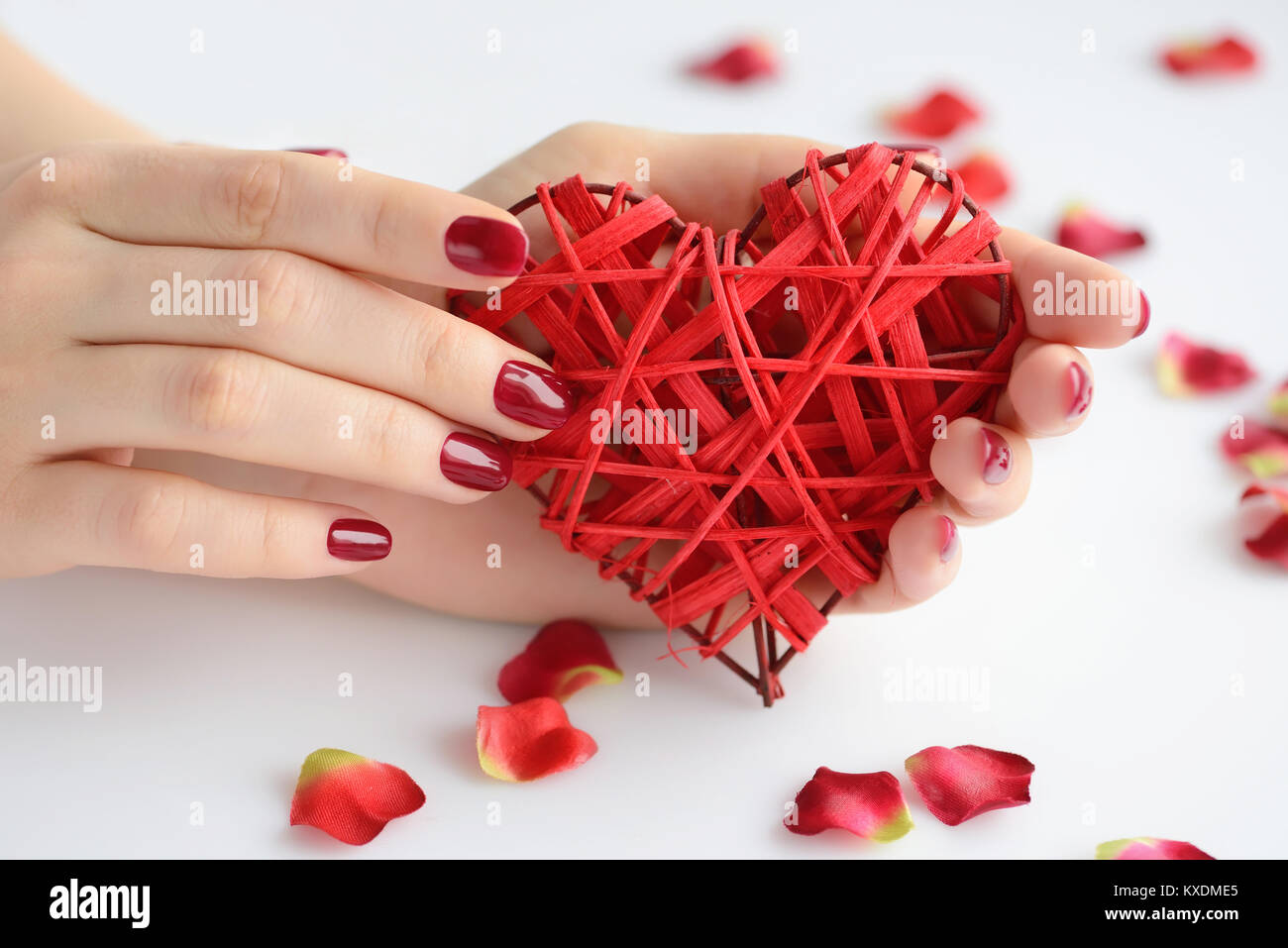 Wicker red heart in woman's hands on white background. Closeup heart in ...