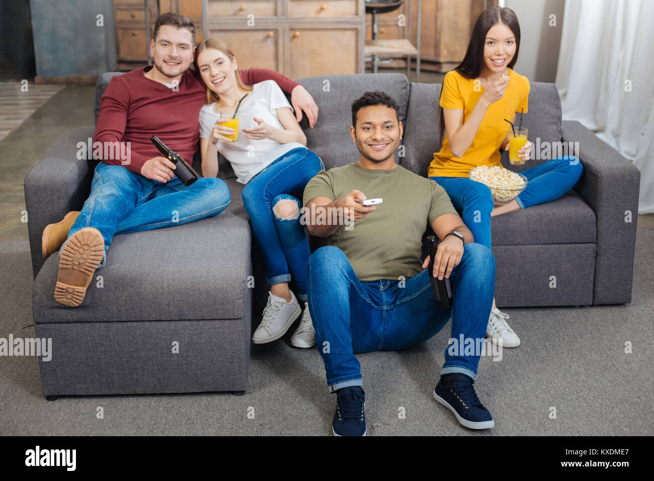 Smiling couple hugging while watching TV with friends Stock Photo - Alamy