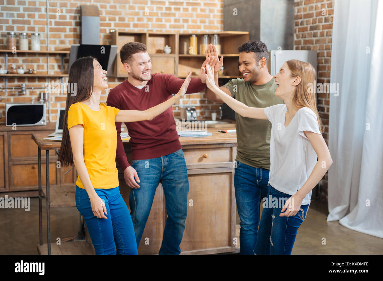Positive friends laughing while giving five to each other Stock Photo ...