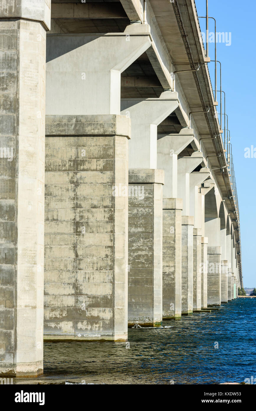 Concrete bridge over water. Gray pillars support the weight of the ...