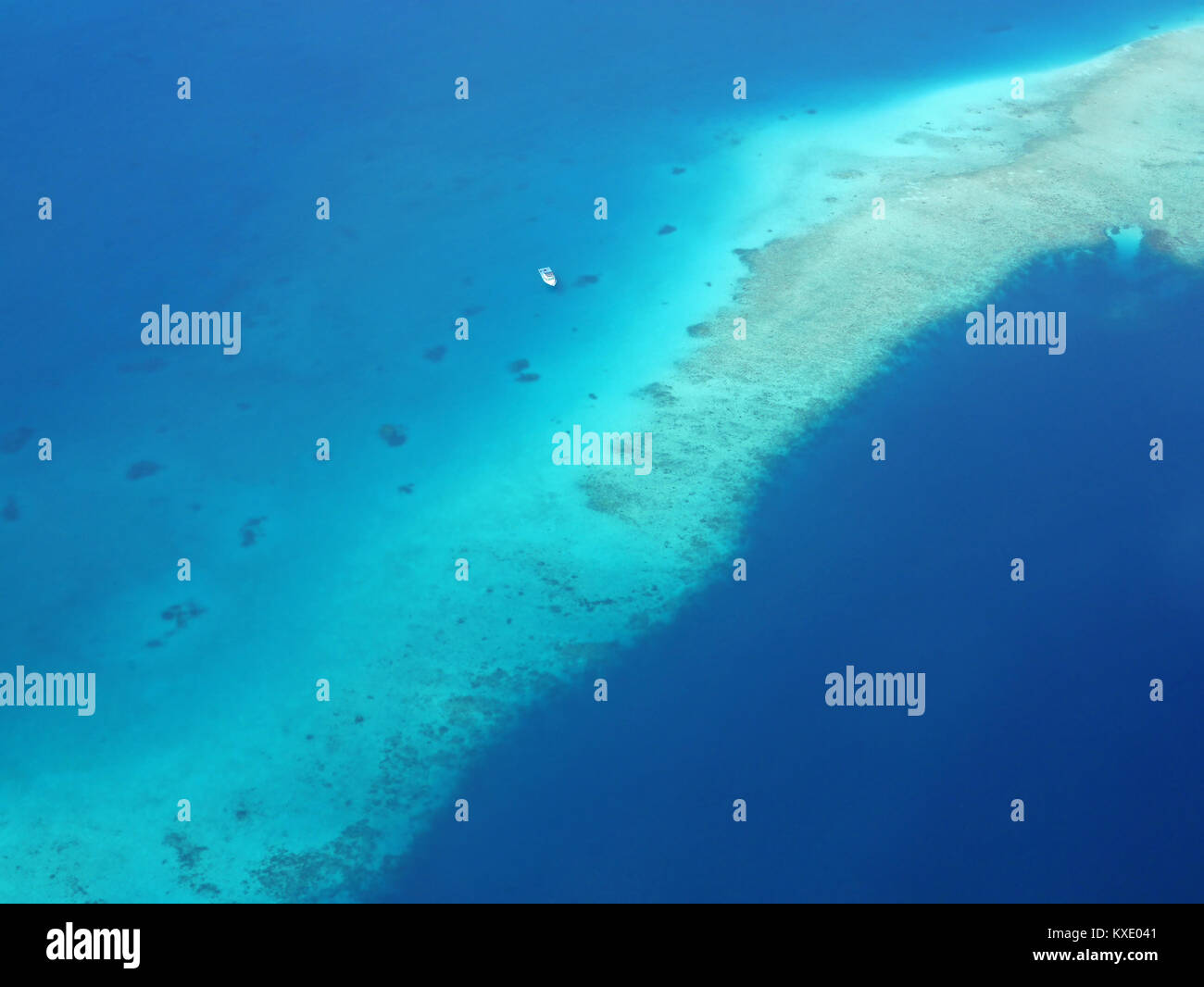 Aerial view of tourist ferry boat floating near coral reef of atoll in ...
