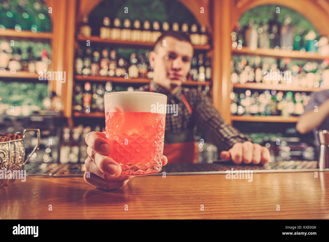 Barman offering an alcoholic cocktail at the bar counter on the bar ...