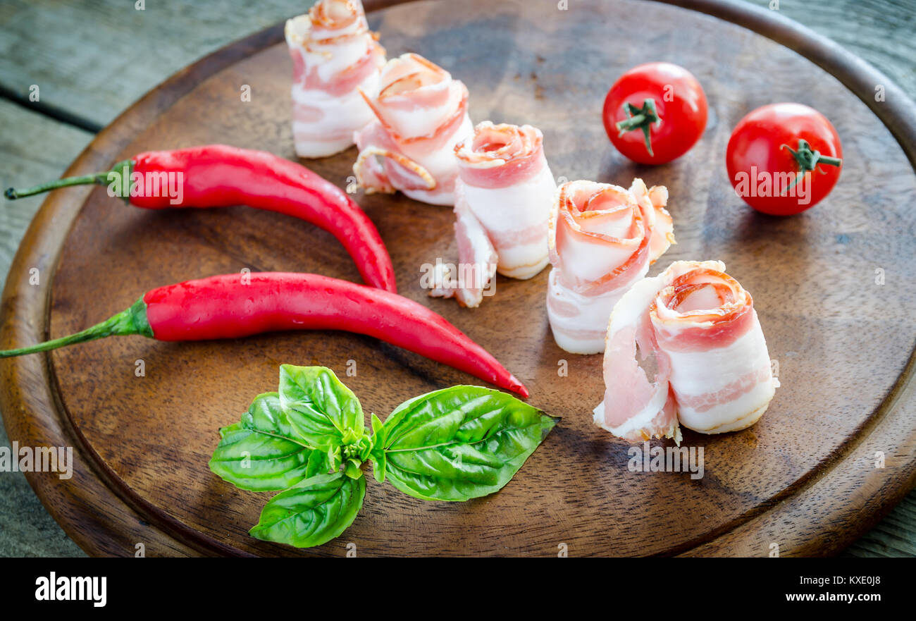 Rolled bacon strips on wooden board Stock Photo - Alamy