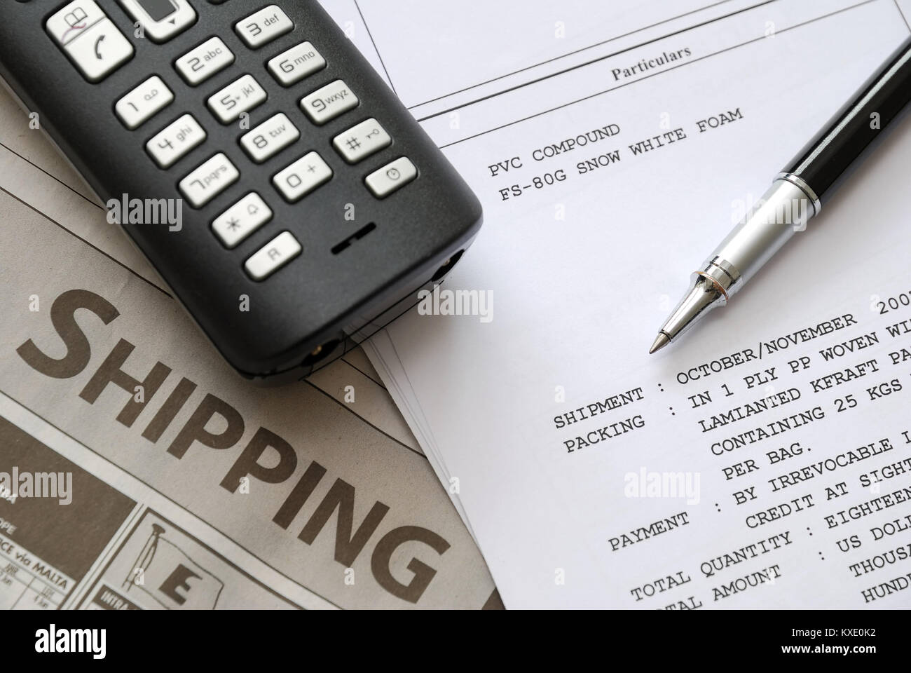 Shipping invoices and newspaper with pen on related documents. For ...