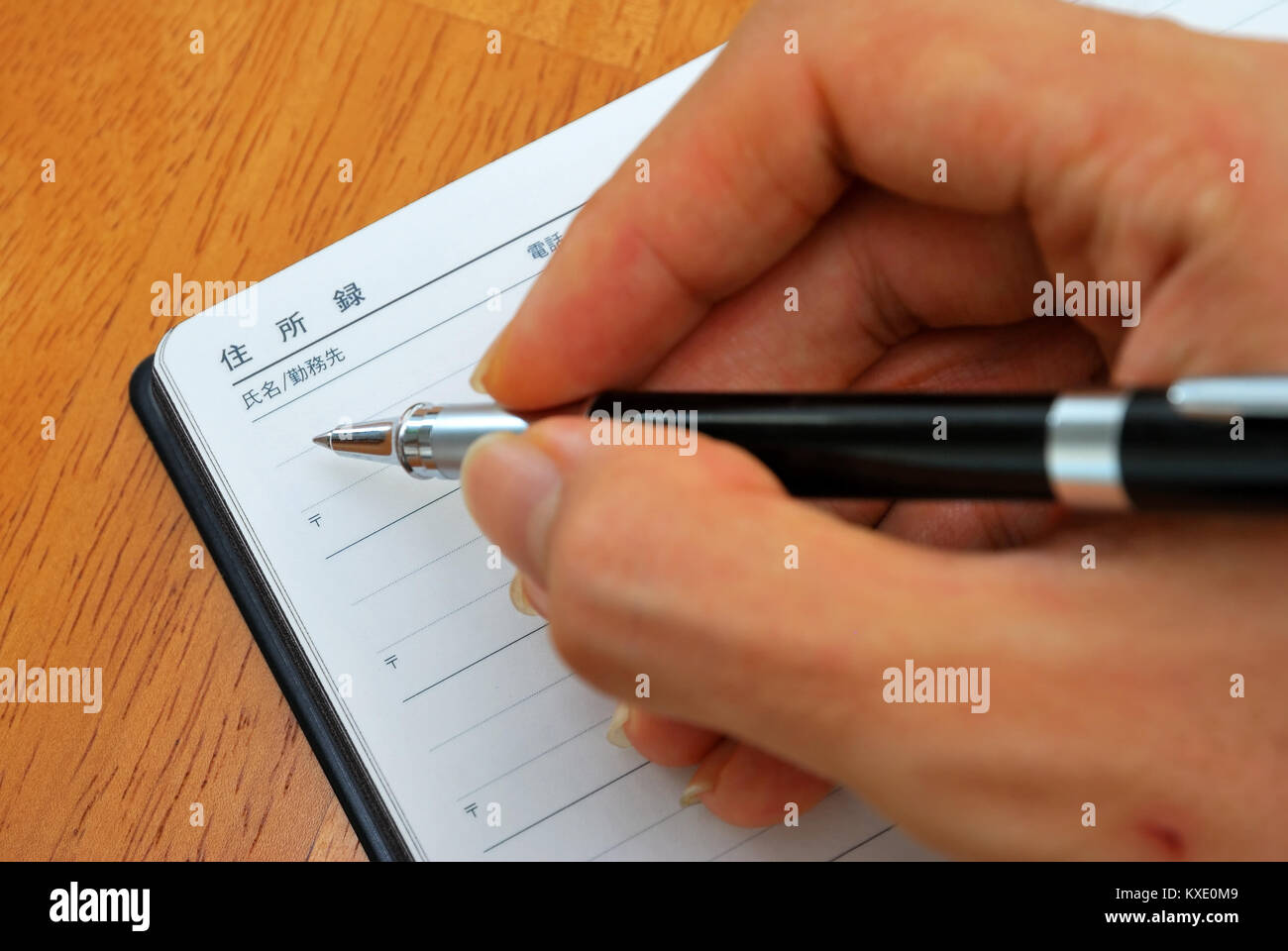 Hand writing with pen on Japanese address book signifying concepts such ...