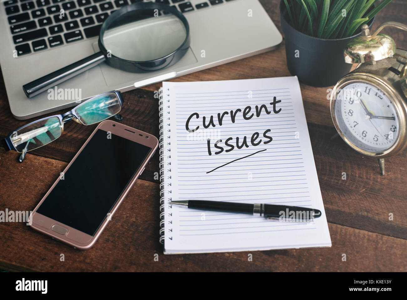 notebook, laptop, smartphone, clock and pen with CURRENT ISSUES word on ...