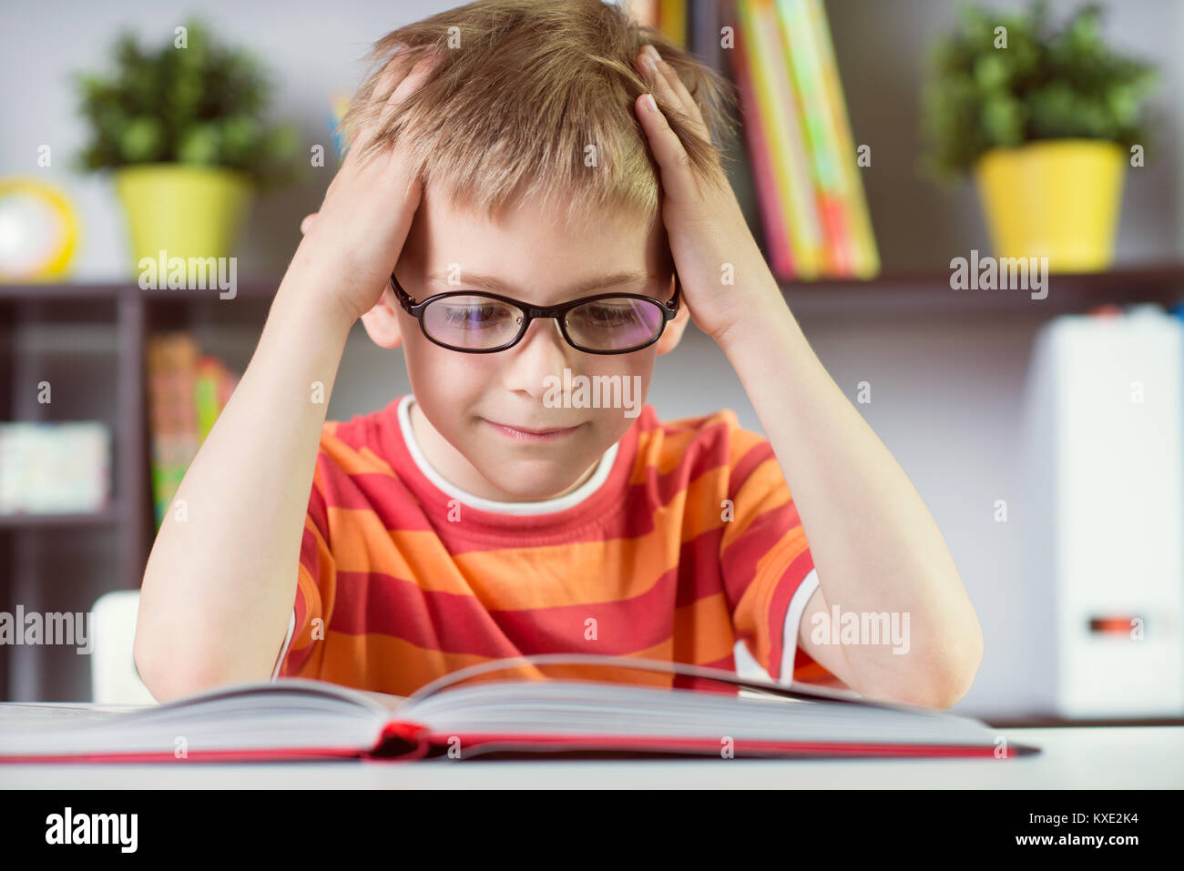 Elementary school boy at classroom desk reading boock Stock Photo - Alamy
