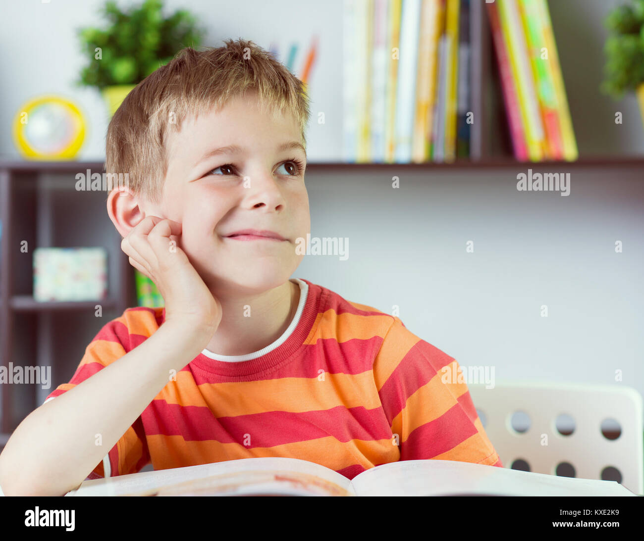 Elementary school boy at classroom desk reading boock Stock Photo - Alamy