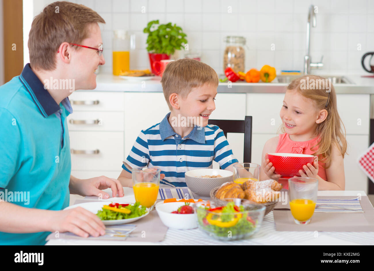 Smiling family eating breakfast together in kitchen Stock Photo - Alamy
