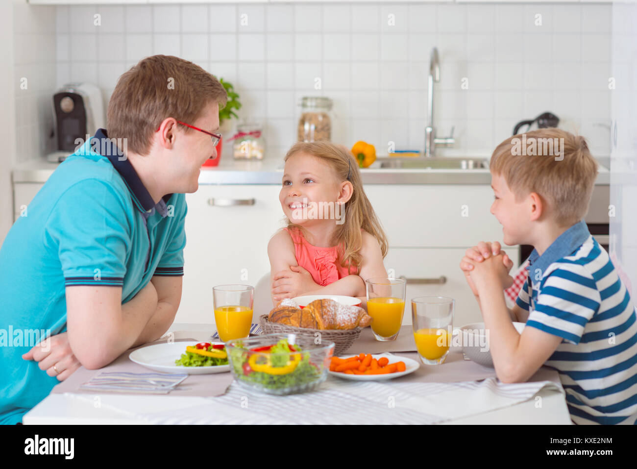 Smiling family eating breakfast together in kitchen Stock Photo - Alamy