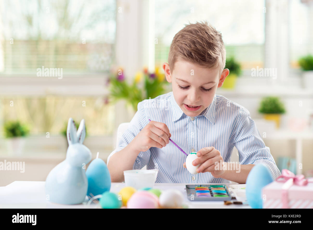 Happy child boy having fun during painting eggs for easter in spring at ...