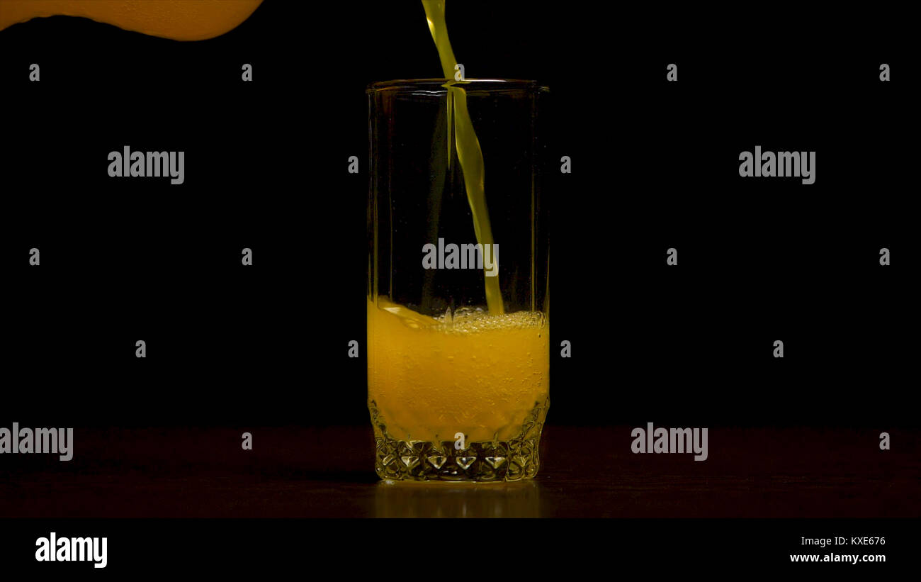 Orange soda large glass, overflowing glass of orange soda closeup with bubbles isolated on black ...