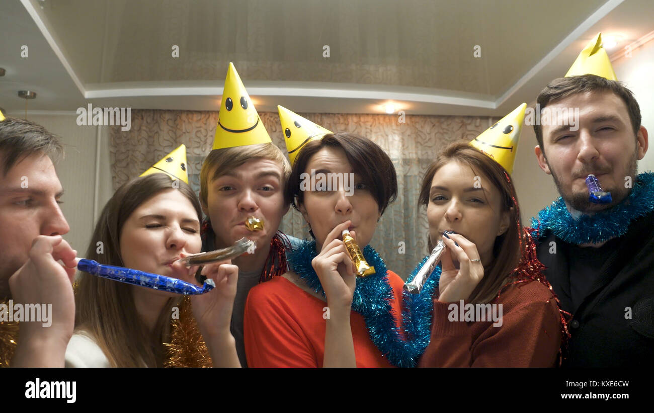 Friends with party hat blowing and having fun. Friends with party hats ...