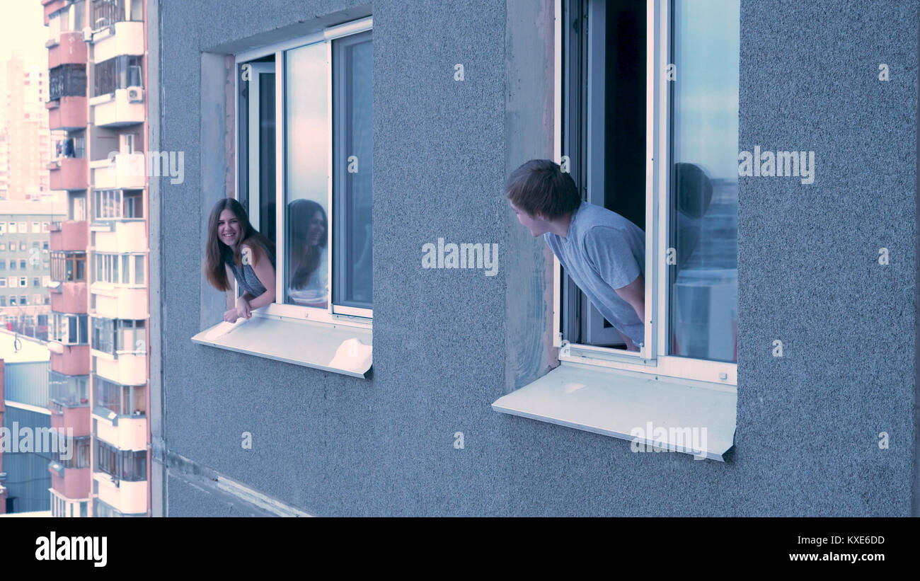 Neighbors talk to each other from the window. Young happy couple ...