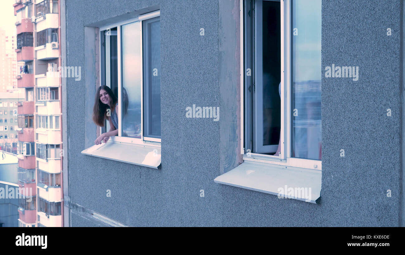 Neighbors talk to each other from the window. Young happy couple ...
