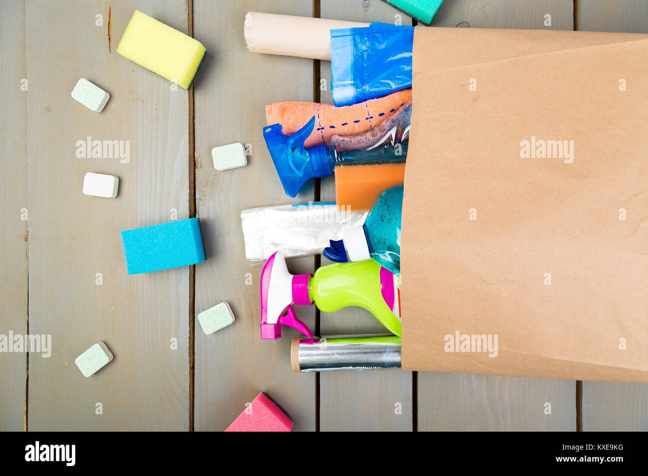 Full paper bag of different house cleaning product on wooden table ...