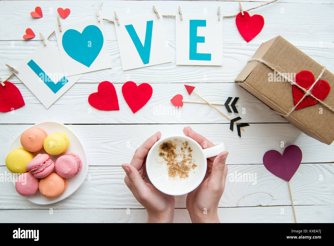 Top view of human hands holding cup of cappuccino with macaroon cookies ...